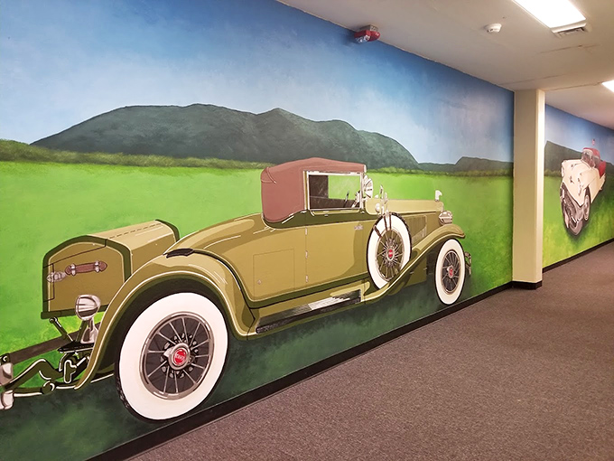 Art meets automotive history in this corridor mural, where classic cars roll eternally through an idealized American landscape.