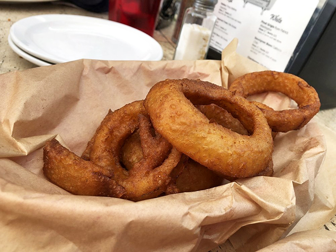 Onion rings that shatter with each bite, nestled in brown paper like precious golden treasures – worth every calorie and every napkin.