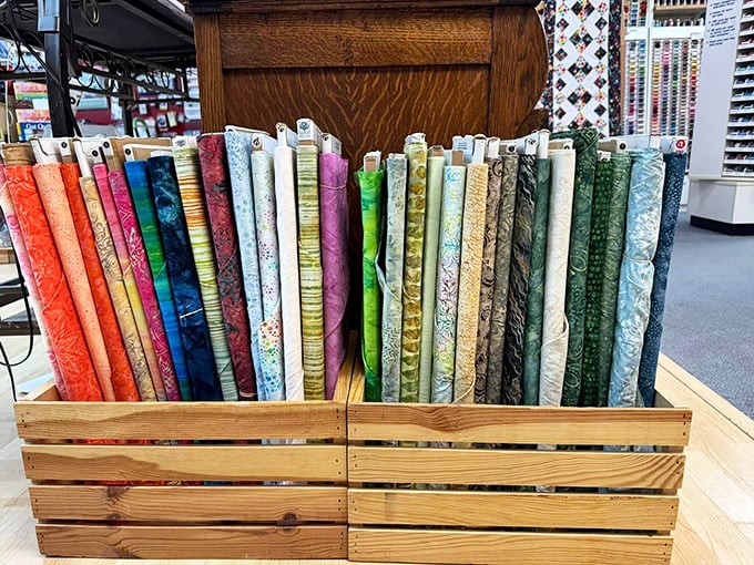 Wooden crates displaying fabric rolls like fine wines. "Ah yes, the 2023 floral cotton. Note the subtle undertones of whimsy."