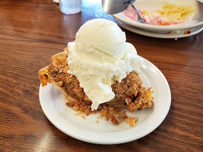 Not just pie—it's a crumbly, cinnamon-scented time machine to your grandmother's kitchen, complete with ice cream melting into every perfect crevice.