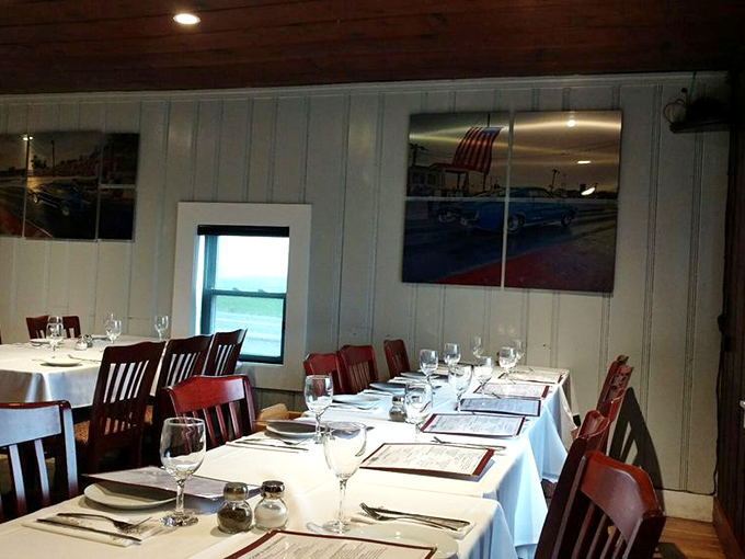 The dining room at Wilcom's—where white tablecloths meet nautical photographs in a space that says "we respect both the food and you."