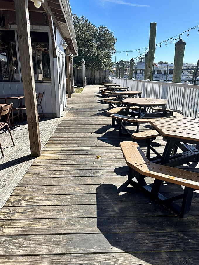 Morning sunlight bathes the weathered deck in golden warmth—empty tables patiently waiting for the day's seafood pilgrims to arrive.