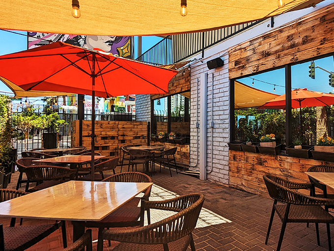 Vegas sunshine filtered through coral umbrellas creates the perfect outdoor dining microclimate. Even the bricks underfoot seem to radiate contentment.