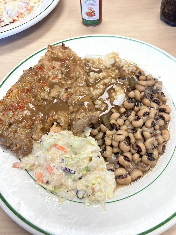 This smothered pork chop with its savory gravy isn't just food—it's therapy on a plate. The black-eyed peas are playing backup to a culinary rock star.