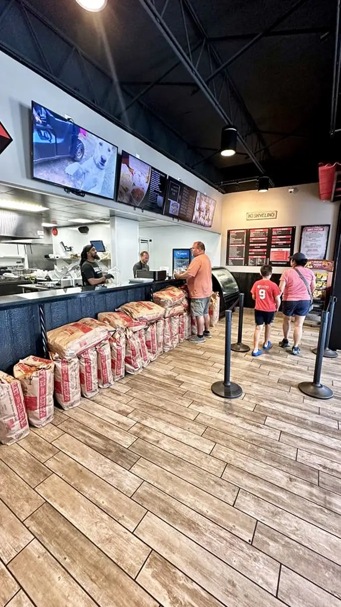 The pilgrimage to the counter—where hungry patrons await their turn at the altar of pit beef with the patience of saints.