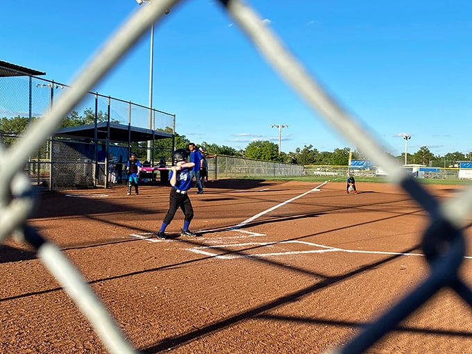 Through the chain-link fence, Russell's softball fields promise the quintessential American summer evening—complete with hot dogs and friendly heckling.