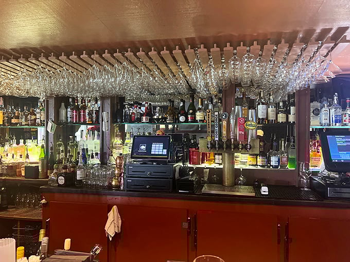 The bar area – where strangers become friends and friends become regulars. Those hanging glasses catch the light like crystal chandeliers.
