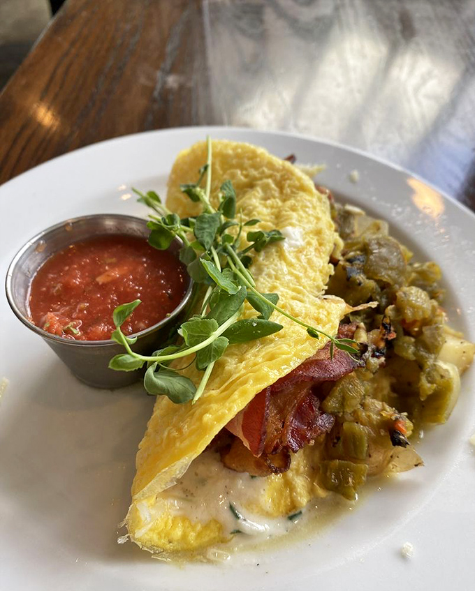 This isn't just an omelet—it's a love letter to breakfast, folded around bacon and vegetables with a side of salsa that makes your standard morning eggs seem like they're not even trying.