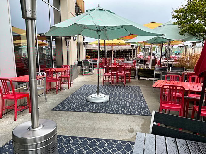 Red chairs pop against mint-green umbrellas in this cheerful outdoor space. Even on cloudy days, this patio promises a bright dining experience.