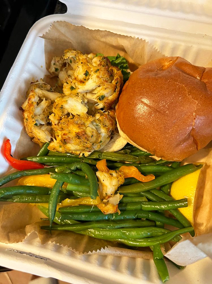 Even in takeout form, the crab cake maintains its dignity—golden brown, accompanied by vibrant green beans that dare you to call them a mere side dish.