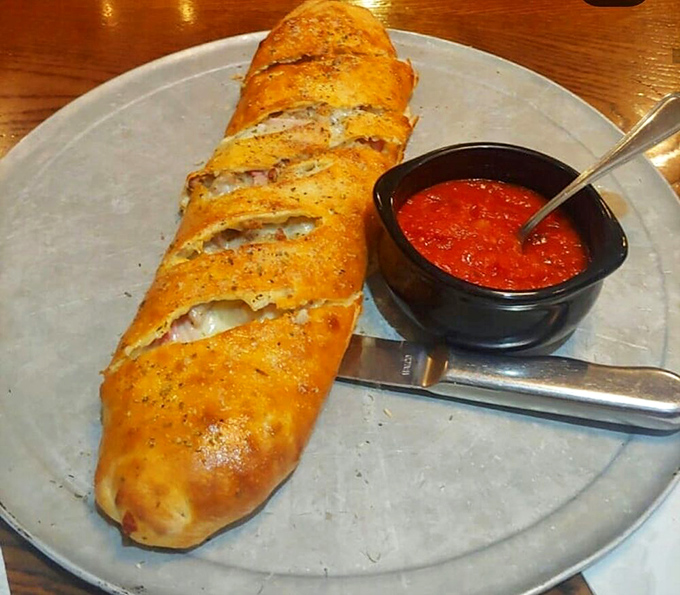 Not just a stromboli—a masterpiece of dough architecture protecting treasures of cheese and filling, with marinara standing guard.