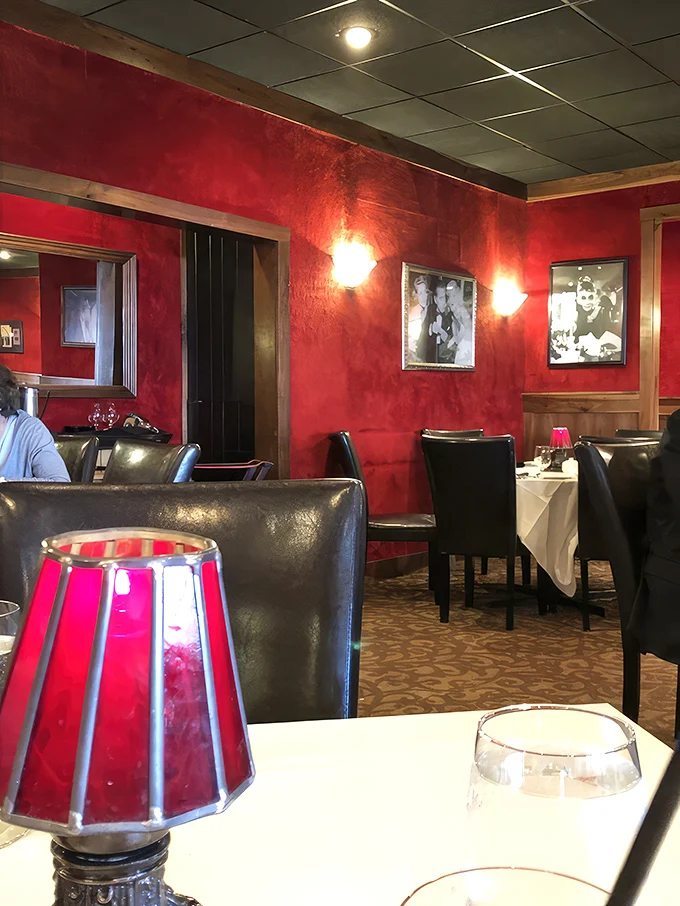The rich red walls and intimate lighting aren't just décor choices—they're mood-setters, creating the perfect backdrop for food worth remembering.