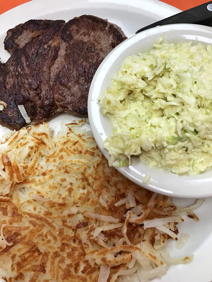 The holy trinity of diner excellence – perfectly seared ribeye, golden hash browns with crispy edges, and creamy slaw creating the perfect balance of textures.