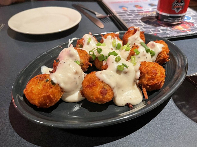 Golden-fried hush puppies (or perhaps spicy Cajun tots) arrive drizzled with creamy sauce—small bites that deliver big Southern comfort.