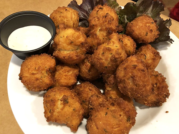 Golden hush puppies with a side of dipping sauce—crispy on the outside, tender within—the kind of appetizer that ruins friendships when the last one remains.