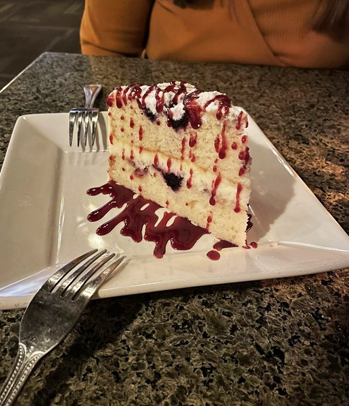 A slice of cake that doesn't just end the meal—it puts an exclamation point on it. That berry sauce is writing love letters across the plate.