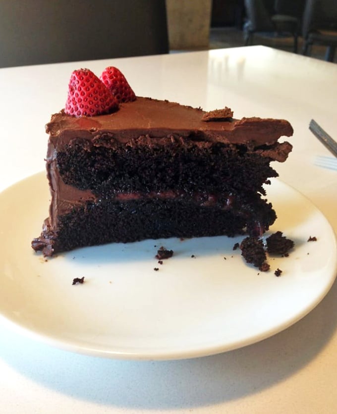 A chocolate cake so dark and rich it could finance its own retirement. Those two strawberries aren't decoration—they're there to make you feel virtuous.
