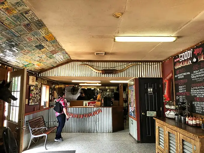License plates from across America tile the ceiling, silent testimonials from barbecue pilgrims who found salvation in this unassuming temple of smoke.