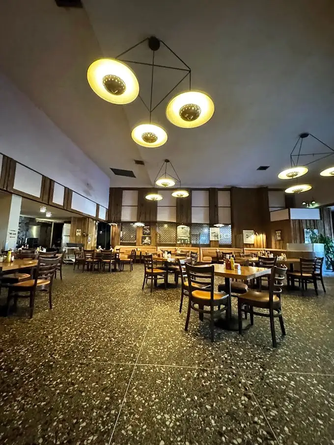 Mid-century modern meets comfort food heaven under these iconic circular lights. The empty tables won't stay that way long—this place fills up faster than your grandmother's kitchen at holiday time.