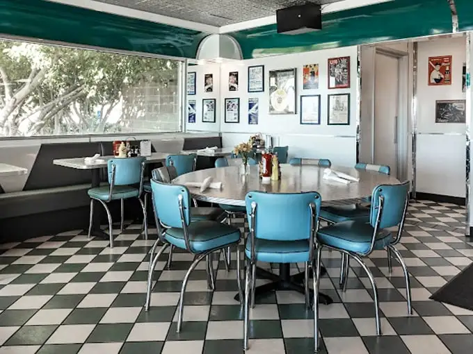 Those turquoise chairs aren't just seating—they're time machines. The checkerboard floor and chrome accents transport you to an era when conversations happened face-to-face, not screen-to-screen.