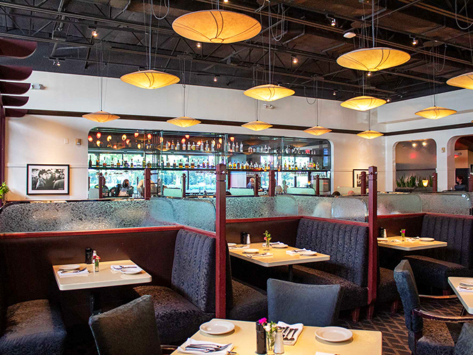 Amber pendant lights cast a golden glow over intimate booths, creating that rare atmosphere where both first dates and family reunions feel equally at home.