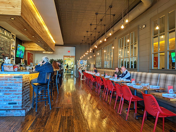 Warm wood floors reflect pendant lighting while red chairs pop against neutral tones. This isn't just a restaurant—it's Little Rock's living room with better food.