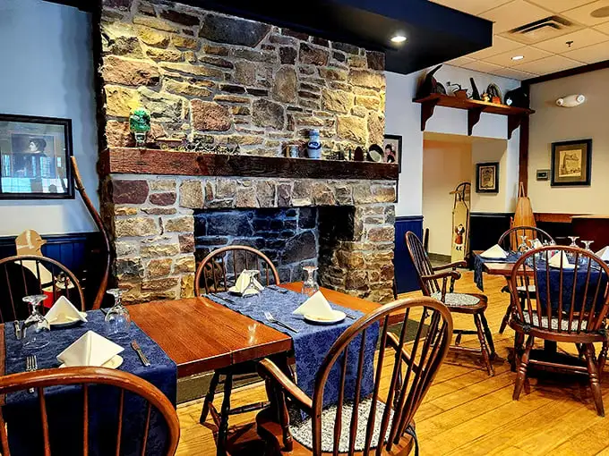 The stone fireplace isn't just for show—it's the beating heart of this dining room where Windsor chairs and wooden tables have witnessed countless "I can't believe how good this is" moments.