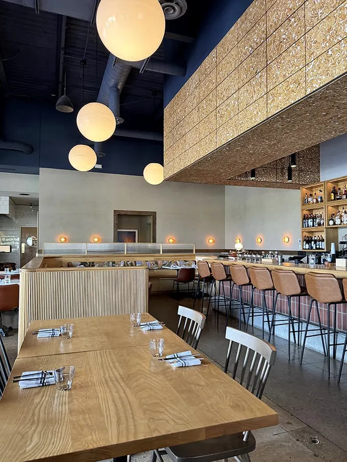 Soaring ceilings, globe pendant lights, and natural wood create a space that's simultaneously modern and timeless—like comfort food with a college degree.