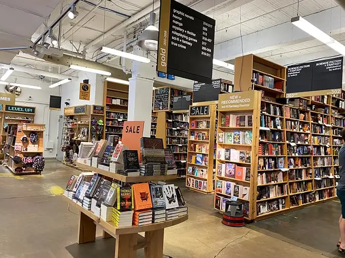 Wooden shelves stretch toward industrial ceilings, creating a bibliophile's playground where new releases mingle with dog-eared classics like old friends at a reunion.