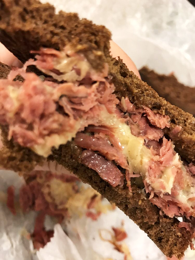 Behold, the hero of our story: layers of pink corned beef and melted cheese between perfect rye, a sandwich worth crossing state lines for.