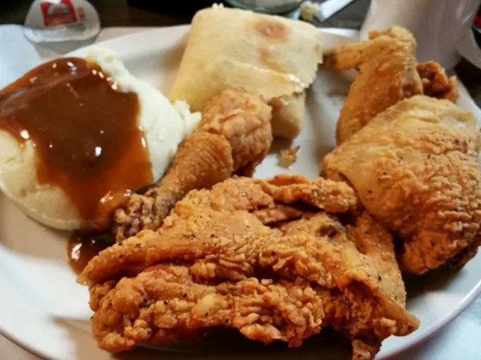 Golden-brown fried chicken with skin that shatters like glass, alongside mashed potatoes drowning in gravy. Comfort food poetry on a plate.