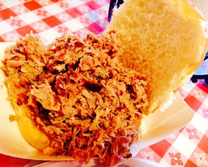 This pulled pork sandwich isn't just a meal, it's a masterclass in barbecue architecture – a perfect ratio of meat to bun that'll haunt your dreams.