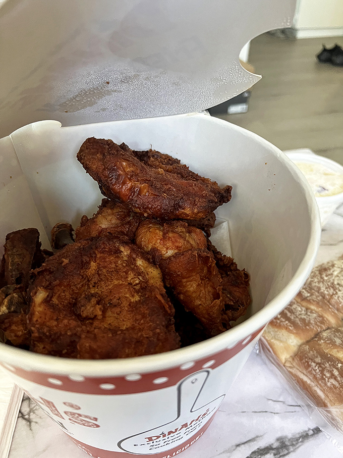 Golden-brown pieces nestled in a paper bucket—this isn't just fried chicken, it's edible nostalgia that crackles with each bite and soothes the soul.
