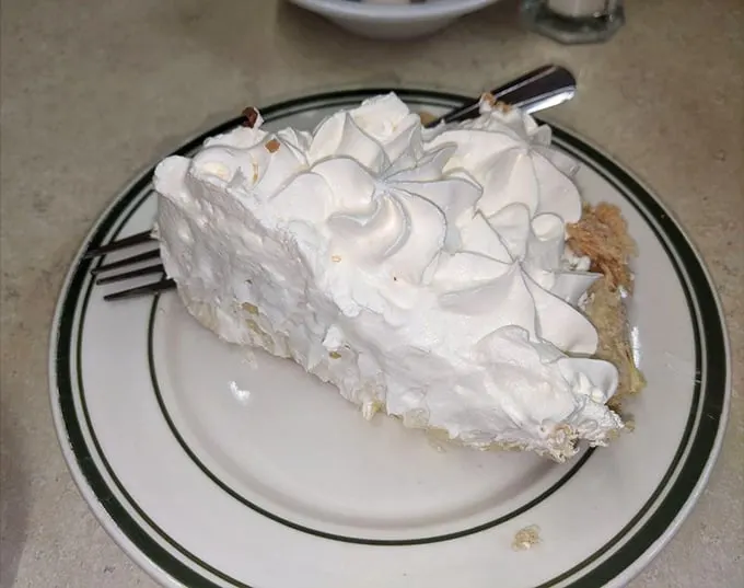 That's not just a slice of coconut cream pie—it's a cloud that somehow landed on a plate, with meringue peaks that would make the Himalayas jealous.