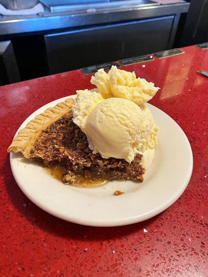 Pecan pie that makes time stand still—warm, gooey center with perfectly toasted nuts and a scoop of vanilla ice cream melting into every crevice.