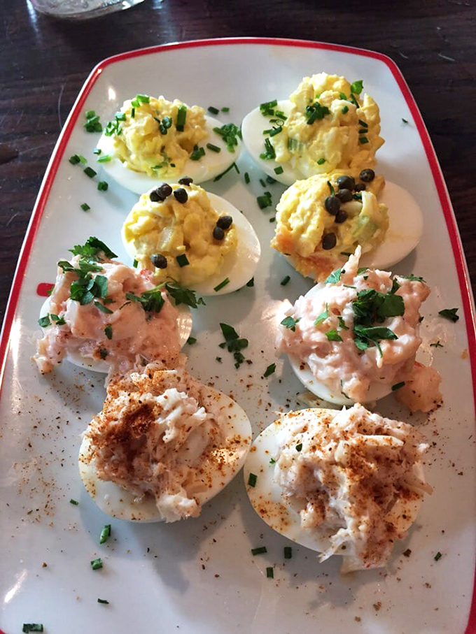 Deviled eggs elevated to an art form! Three distinct varieties showcase the kitchen's creativity—classic paprika, fresh herbs, and what appears to be capers adding playful pops of flavor.