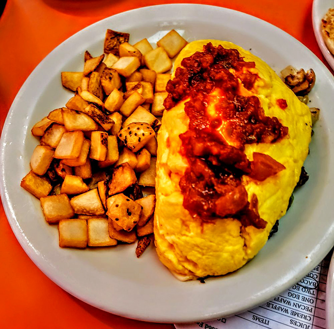 This isn't just an omelet – it's edible architecture with golden eggs embracing steak and cheese, perfectly complemented by crispy cubed home fries.