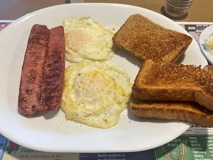 Simplicity perfected: two sunny-side up eggs with perfectly crisped scrapple and toast. In Delaware, this isn't breakfast—it's a birthright.