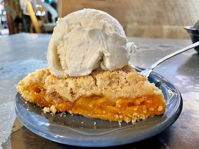 This peach cobbler isn't just dessert—it's summer sunshine captured in a crust, topped with ice cream melting into warm fruit like snowcaps on desert mountains.