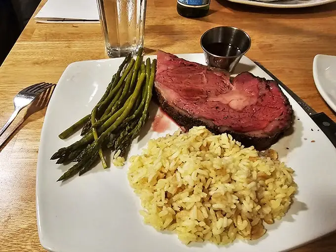 Not just dinner, but a celebration on a plate – perfectly pink prime rib flanked by asparagus soldiers and rice pilaf ready for duty.