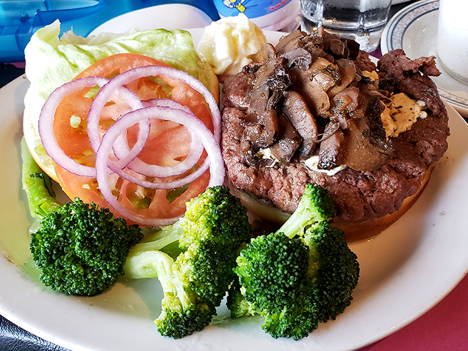 A perfectly seared steak topped with sautéed mushrooms, accompanied by fresh vegetables—proof that sometimes the classics never need reinvention.
