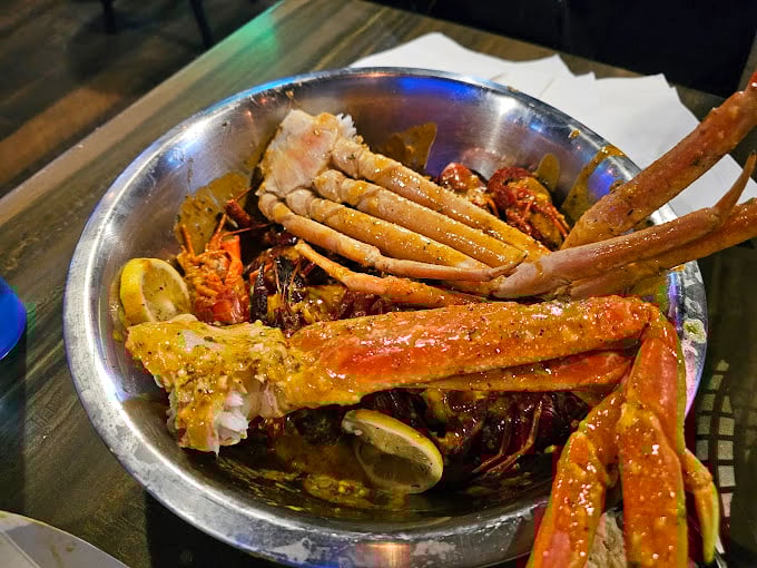 Snow crab legs and crawfish having a pool party in seasoned broth. The lemon wedges aren't just garnish—they're essential equipment for this seafood safari.