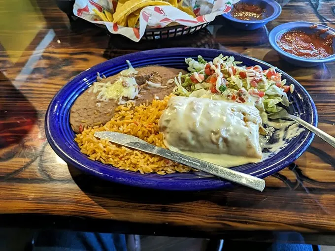 Behold the burrito in its natural habitat—swimming in sauce, surrounded by rice and beans. This plate doesn't just feed you; it embraces you.