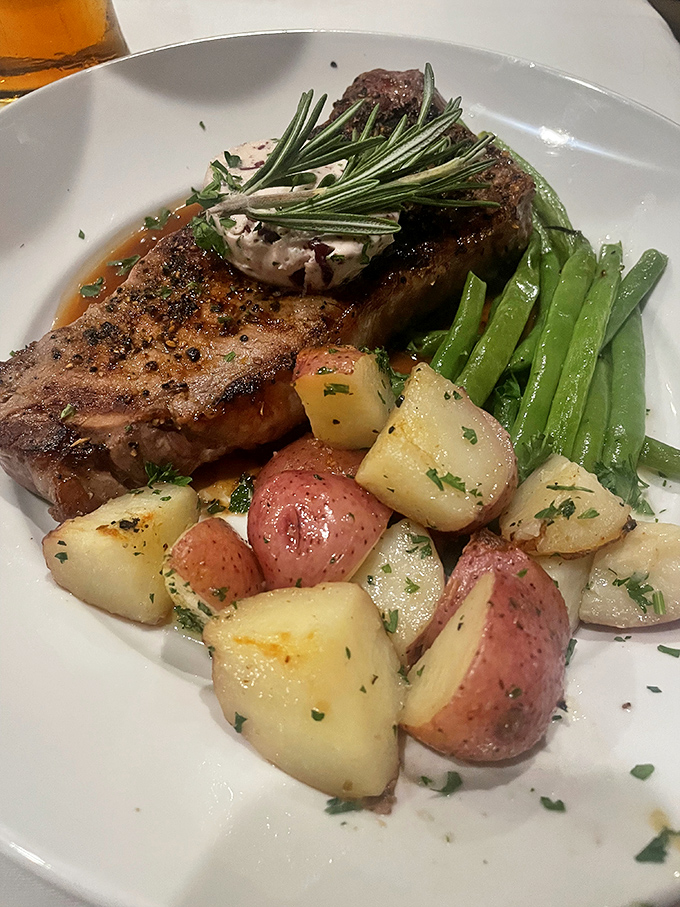 A perfectly cooked steak garnished with fresh rosemary shares the plate with colorful potatoes and vibrant green beans—a trio that performs in perfect harmony.