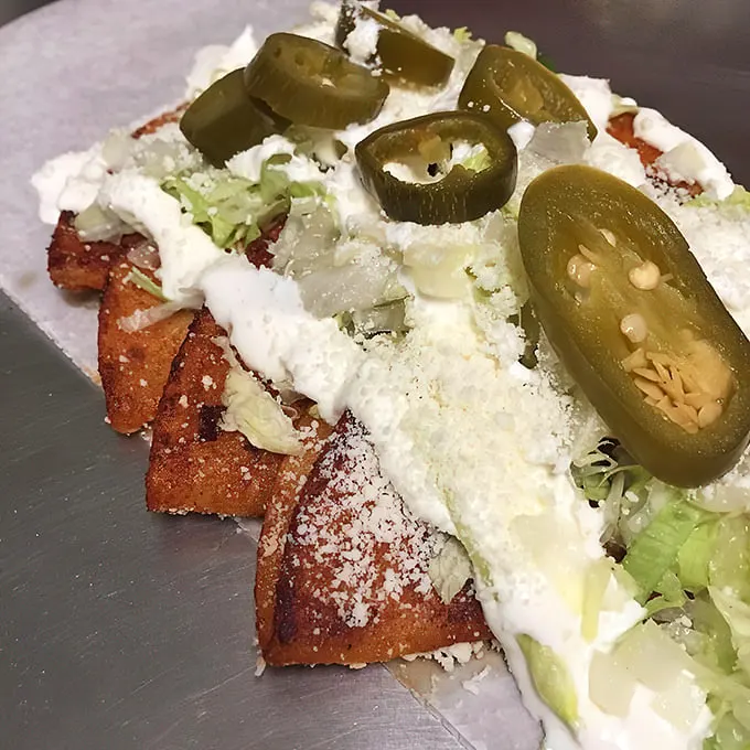 Jalapeños standing guard over enchiladas like tiny green sentinels of spice. They're not just garnish—they're a flavor promise.