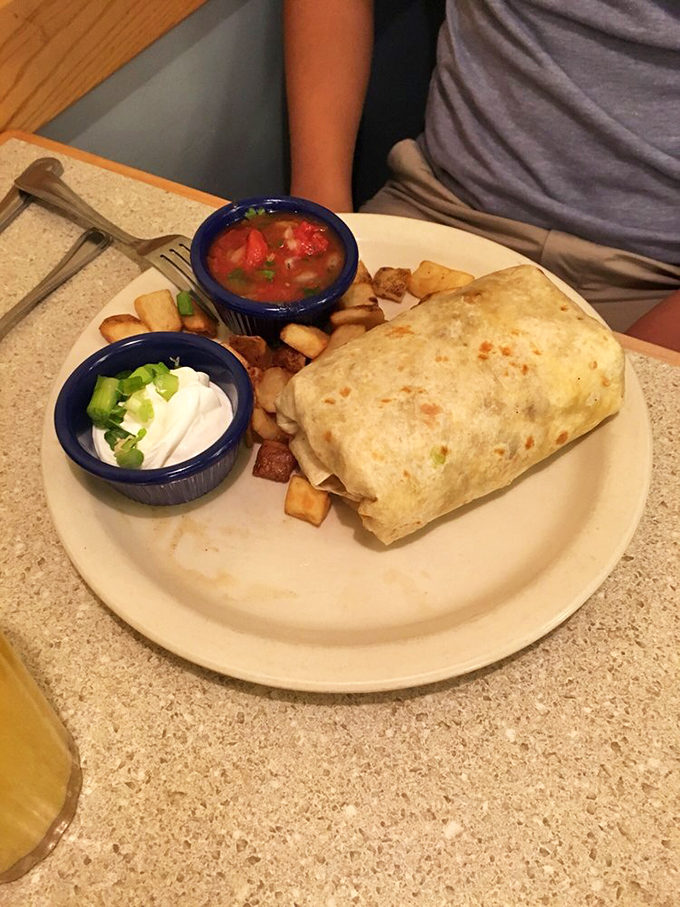 The breakfast burrito in its natural habitat—flanked by salsa and sour cream, surrounded by golden potatoes that could make a French chef weep.