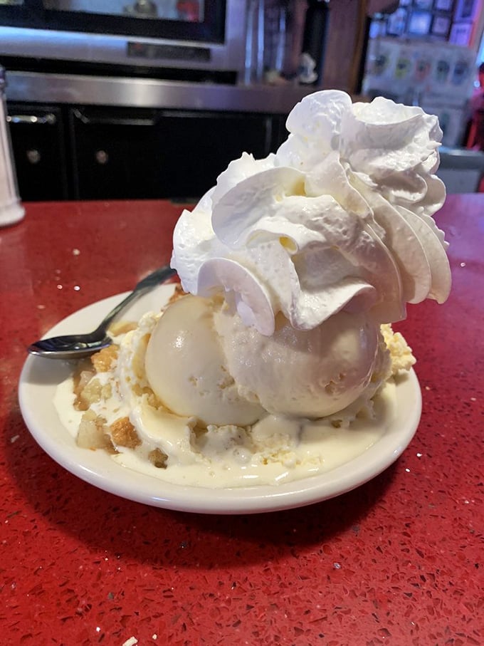 This isn't just dessert, it's architecture—a towering monument to whipped cream engineering atop what might be the world's most perfect ice cream sundae.