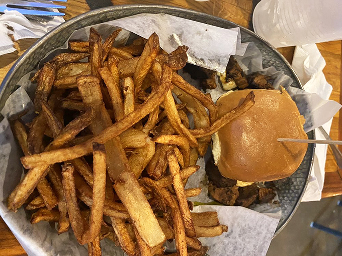 Hand-cut fries surround this burger like a golden moat protecting a castle of flavor. Medieval knights would have fought duels for this plate.