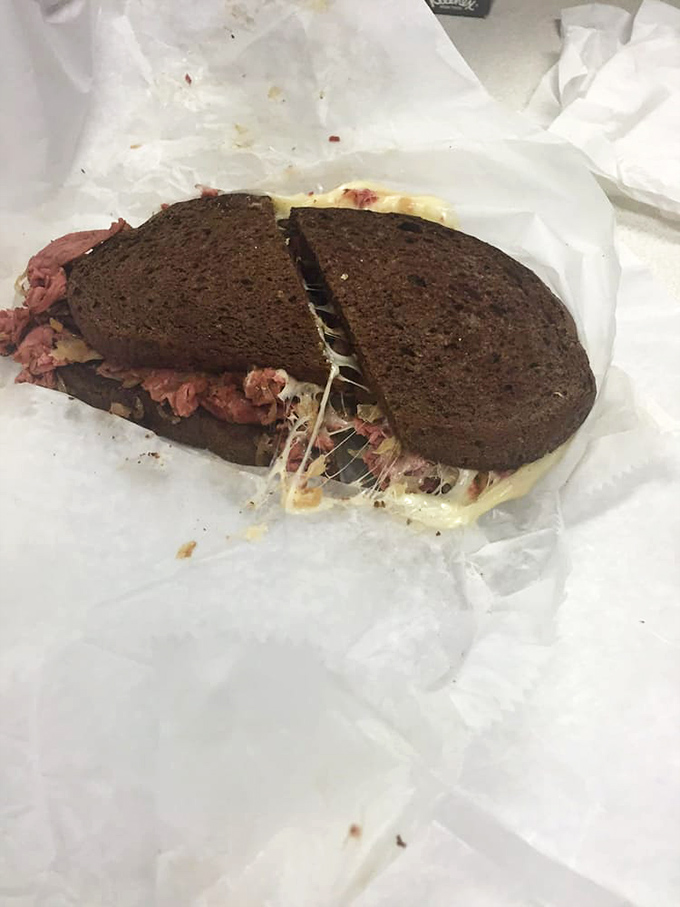Cross-section revelation: this isn't just a sandwich; it's architectural genius with layers of corned beef, Swiss, and sauerkraut in perfect harmony.