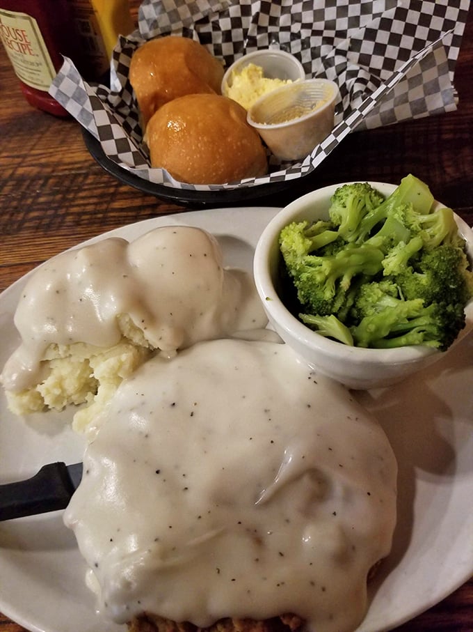 Comfort food nirvana: creamy pepper gravy cascades over golden-fried steak like a delicious waterfall, with mashed potatoes standing by for backup.